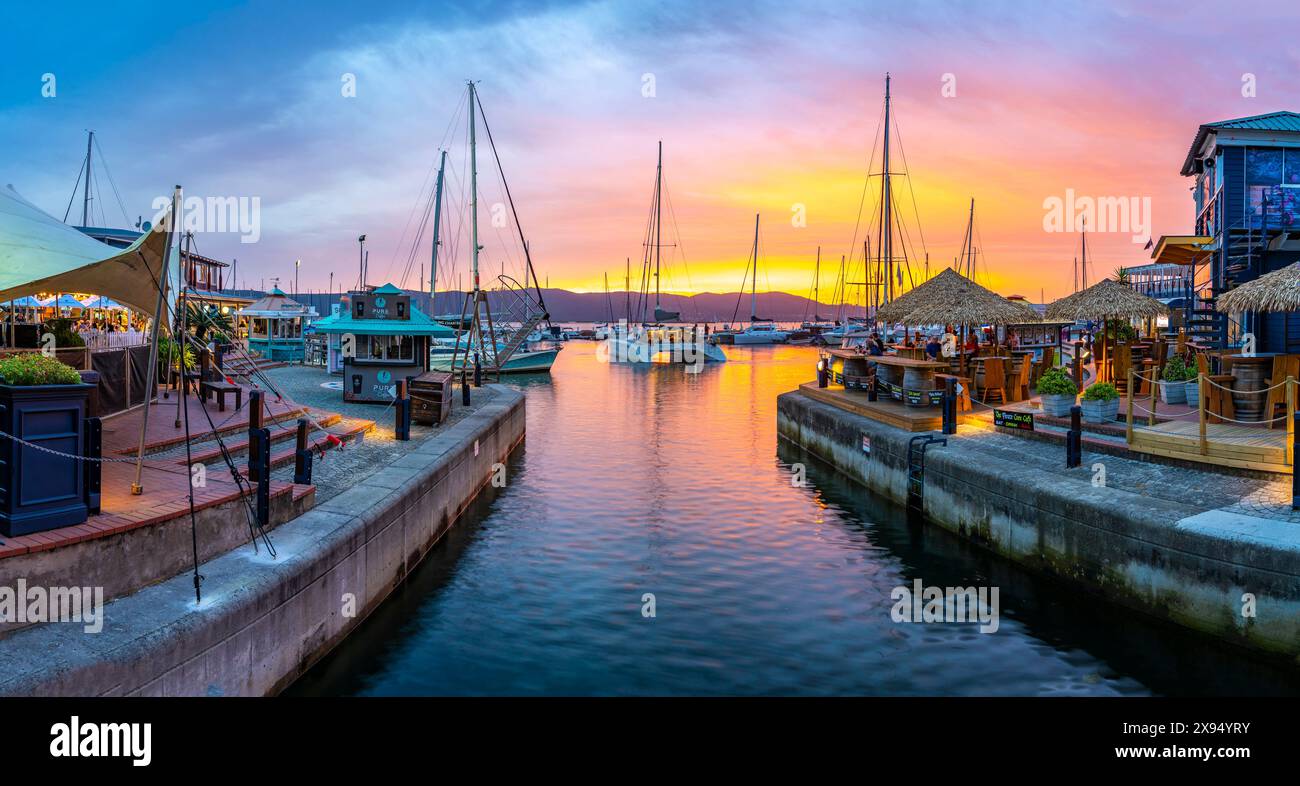 View of golden sunset, boats and restaurants at Knysna Waterfront ...