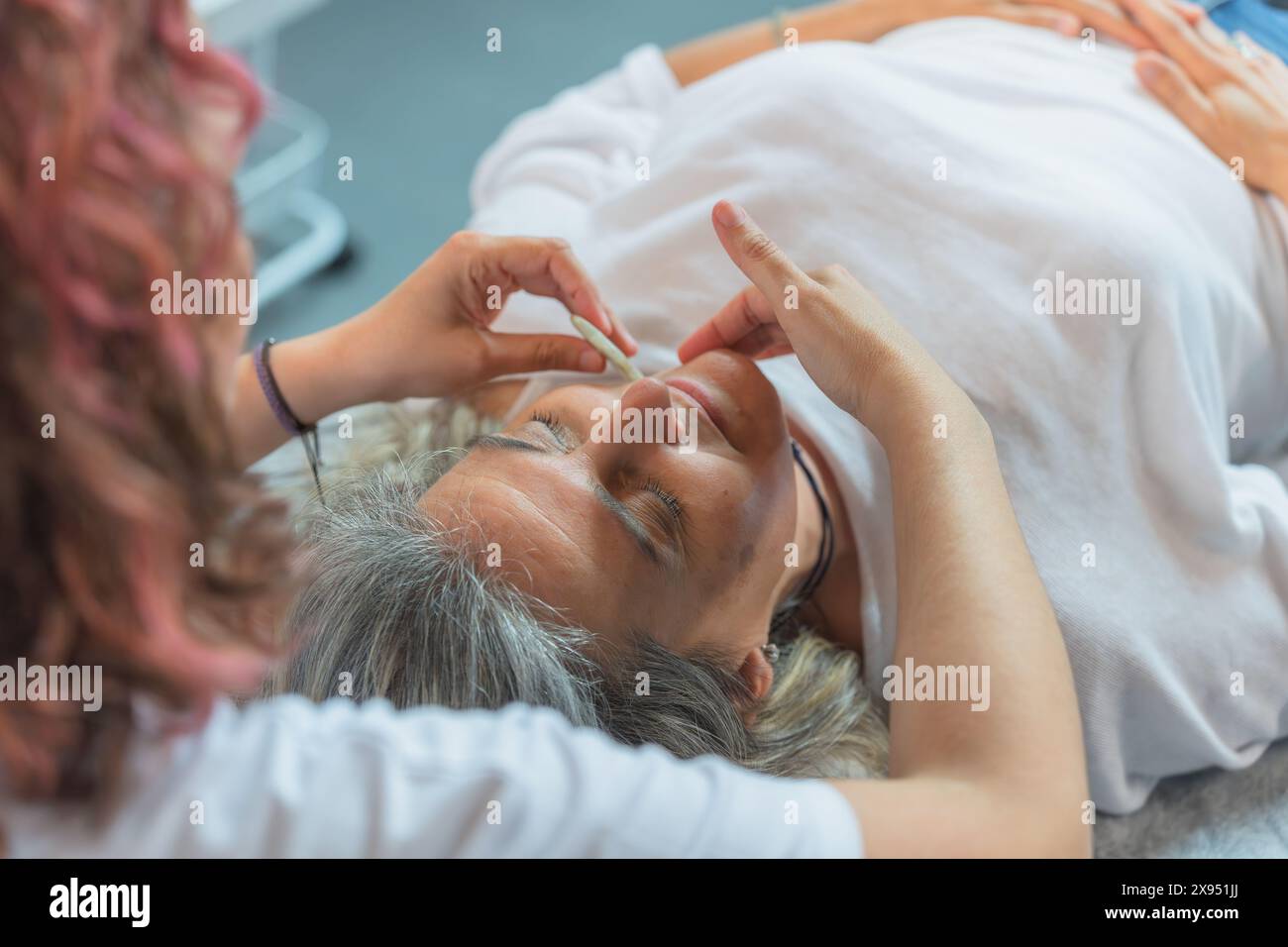 Elderly woman anti aging therapy with a gua sha stone. Skin care ...