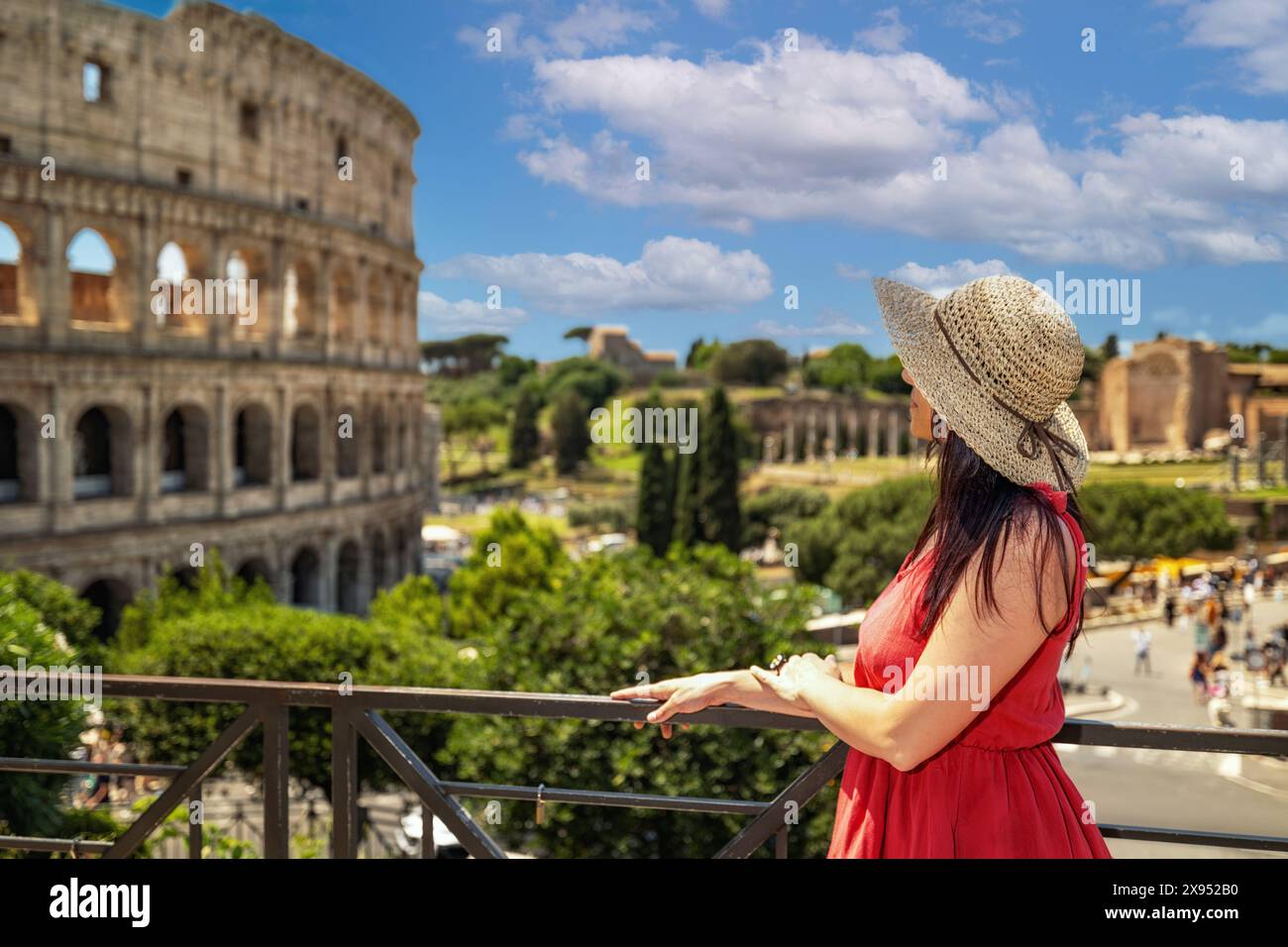 Brunette girl with straw hat admires the majesty of the Colosseum and ...