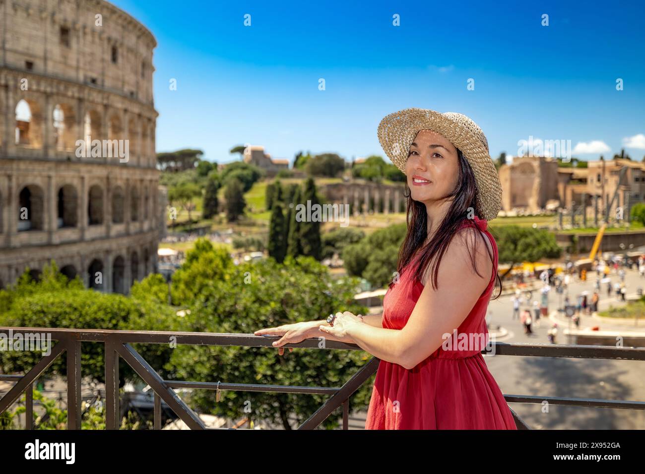 Brunette girl with straw hat admires the majesty of the Colosseum and ...