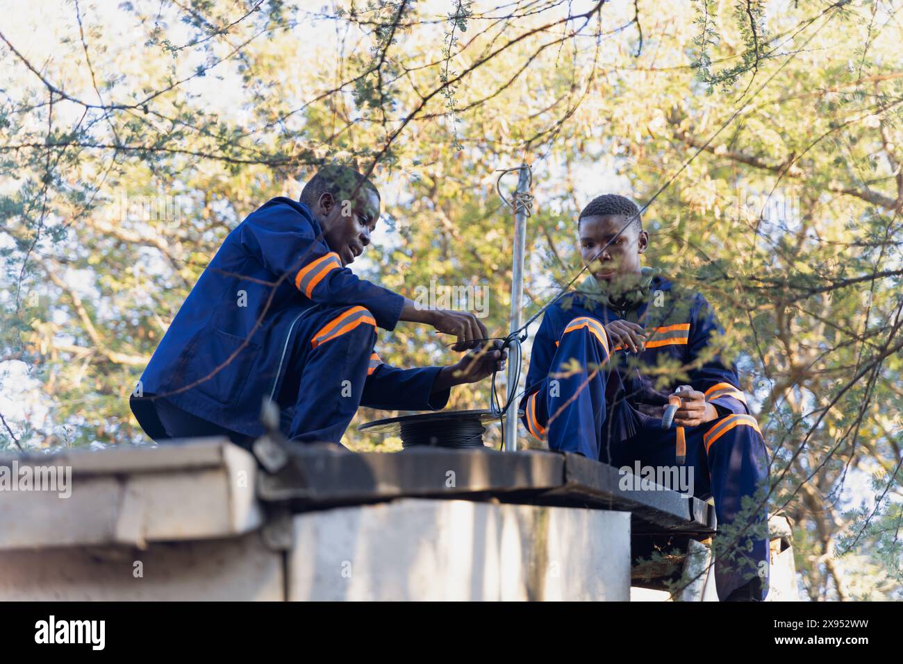 fiber optic cable install, african workers on the roof, roll of cable ...