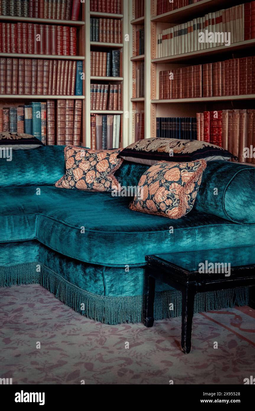 An elegant teal colour sofa in a library in an English stately home ...