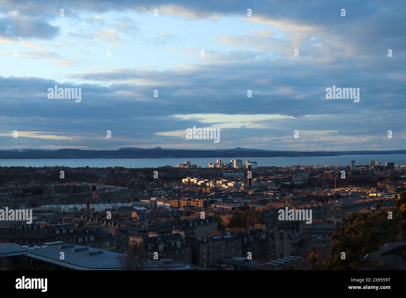 Edinburgh at sunset. The setting sun casts its last rays through thick ...