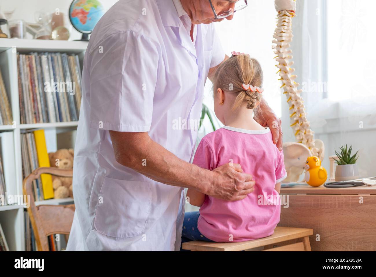 male Orthopedist doctor examining child's back in clinic, physician ...