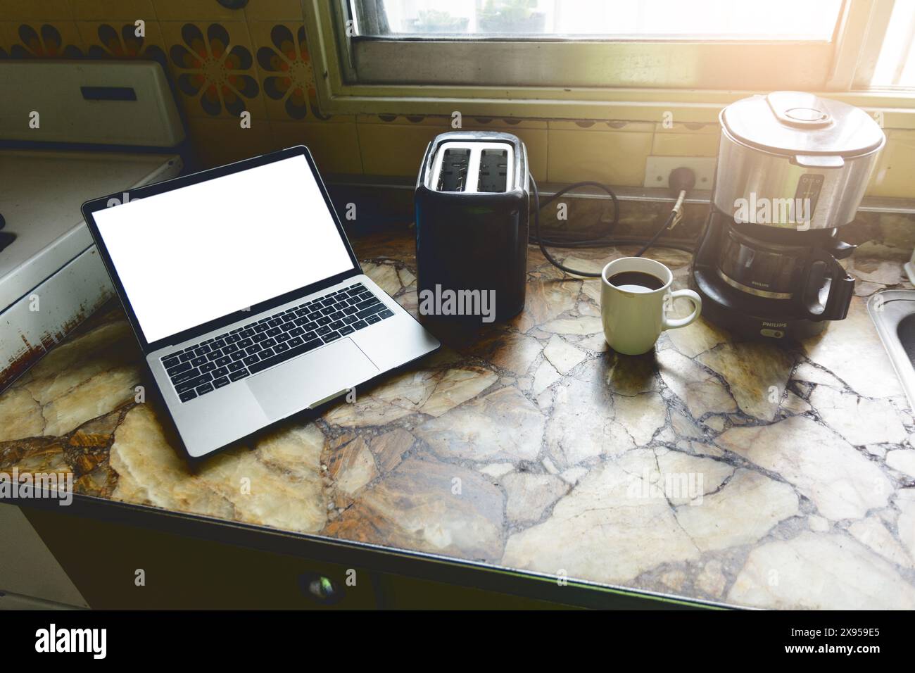 A laptop is open on a counter next to a toaster and a coffee maker. the ...