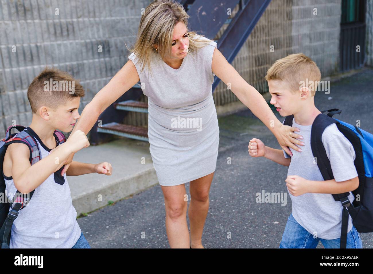 Teacher Stopping Two Boys Fighting In Playground Stock Photo - Alamy