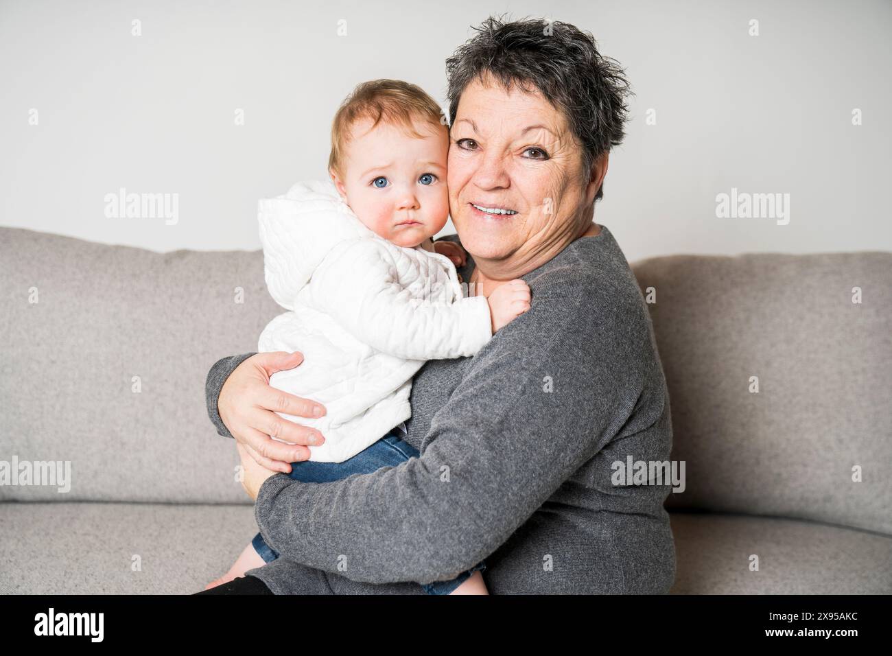 Happy positive baby girl sitting on grandmother knees Stock Photo - Alamy