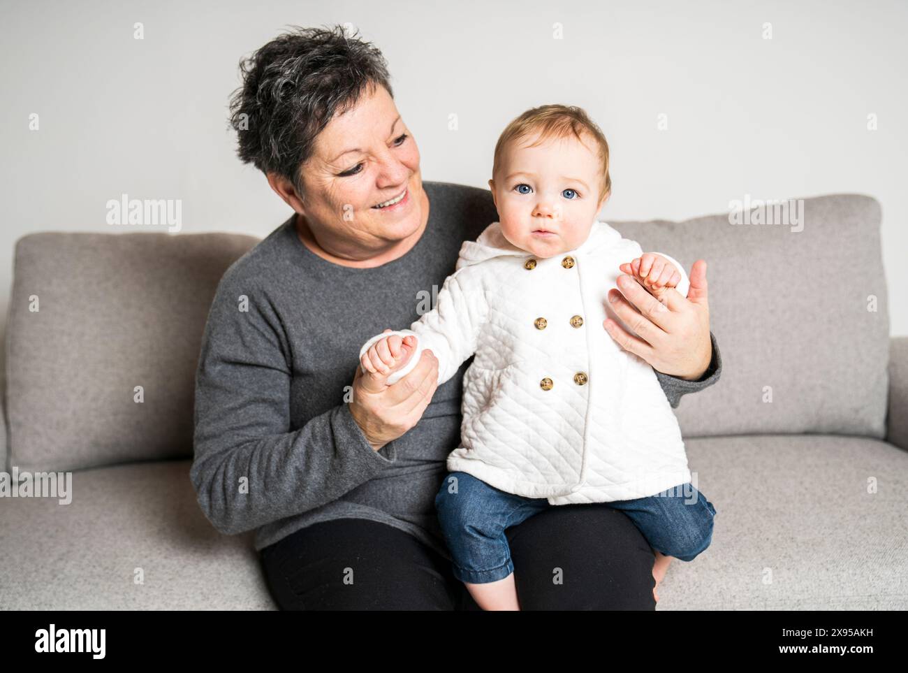 Happy positive baby girl sitting on grandmother knees Stock Photo - Alamy