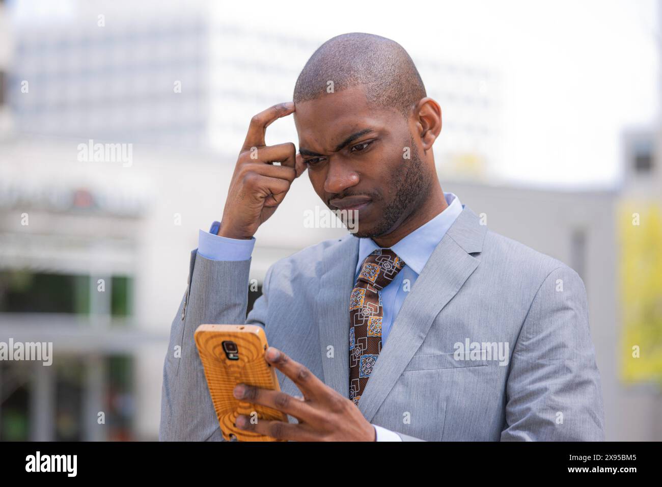 puzzled confused businessman looking at his cellphone thinking what to ...