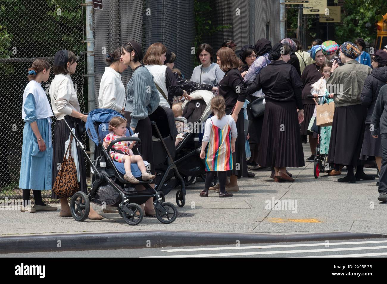 A group of orthodox Jewish women and their daughters wait outside aa ...