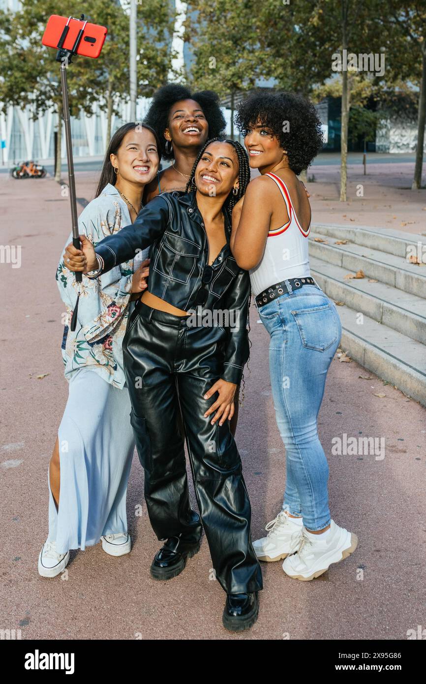 Transgender woman and her female friends use selfie stick and mobile ...