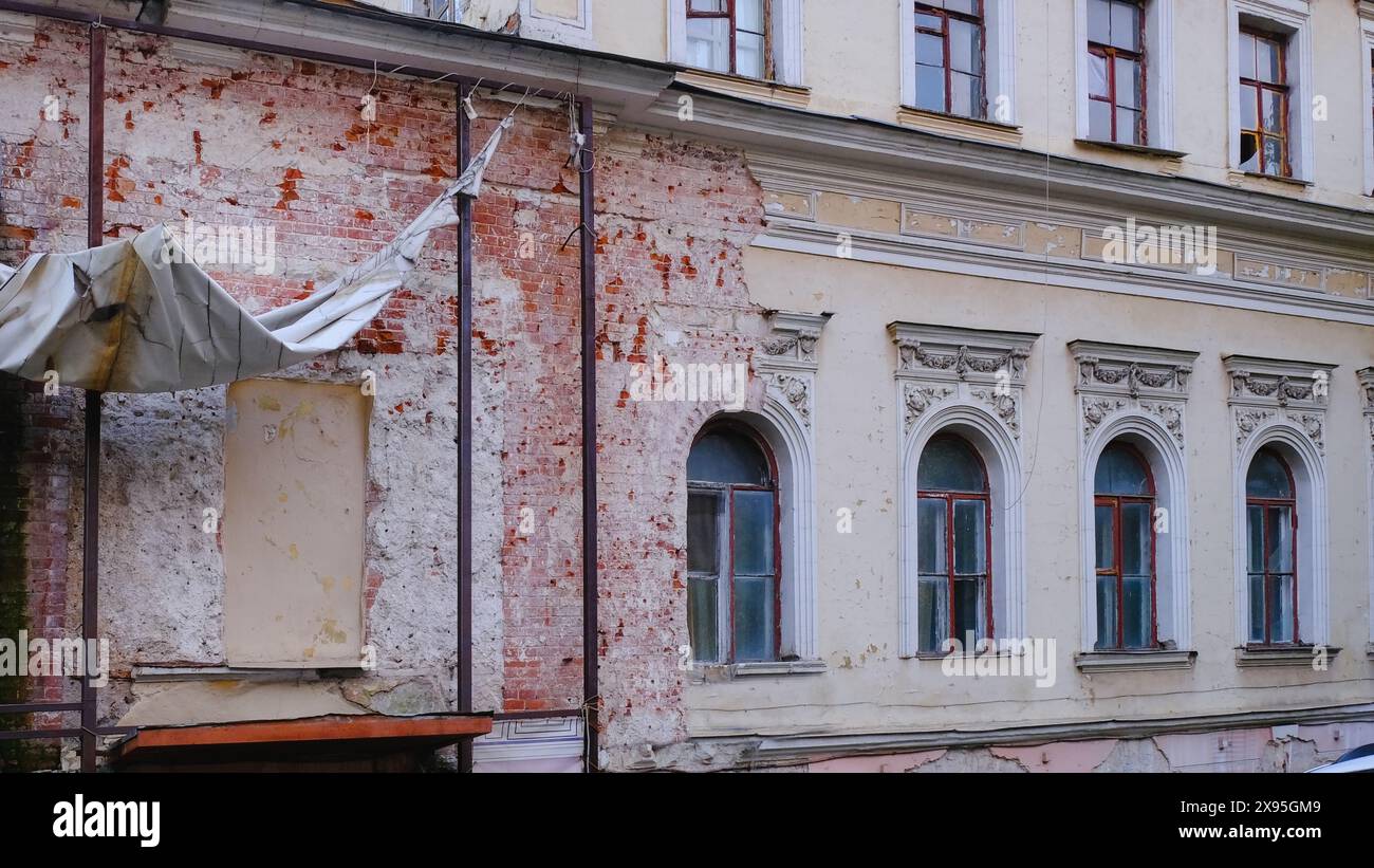 Fragment of facade with ruined windows and crumble stucco fretwork of ...
