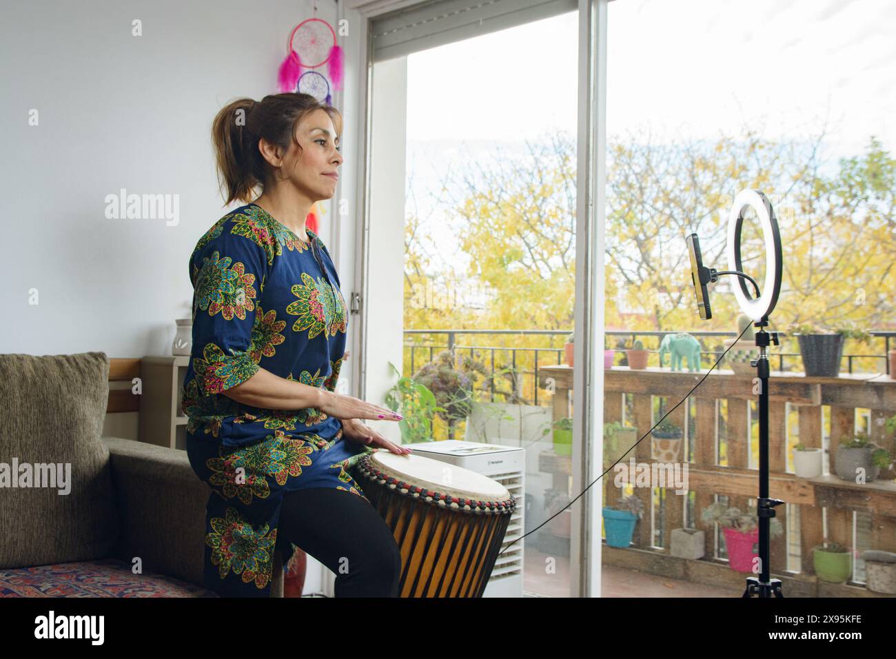 Adult Woman at home Playing the Djembe drum doing a live stream with ...