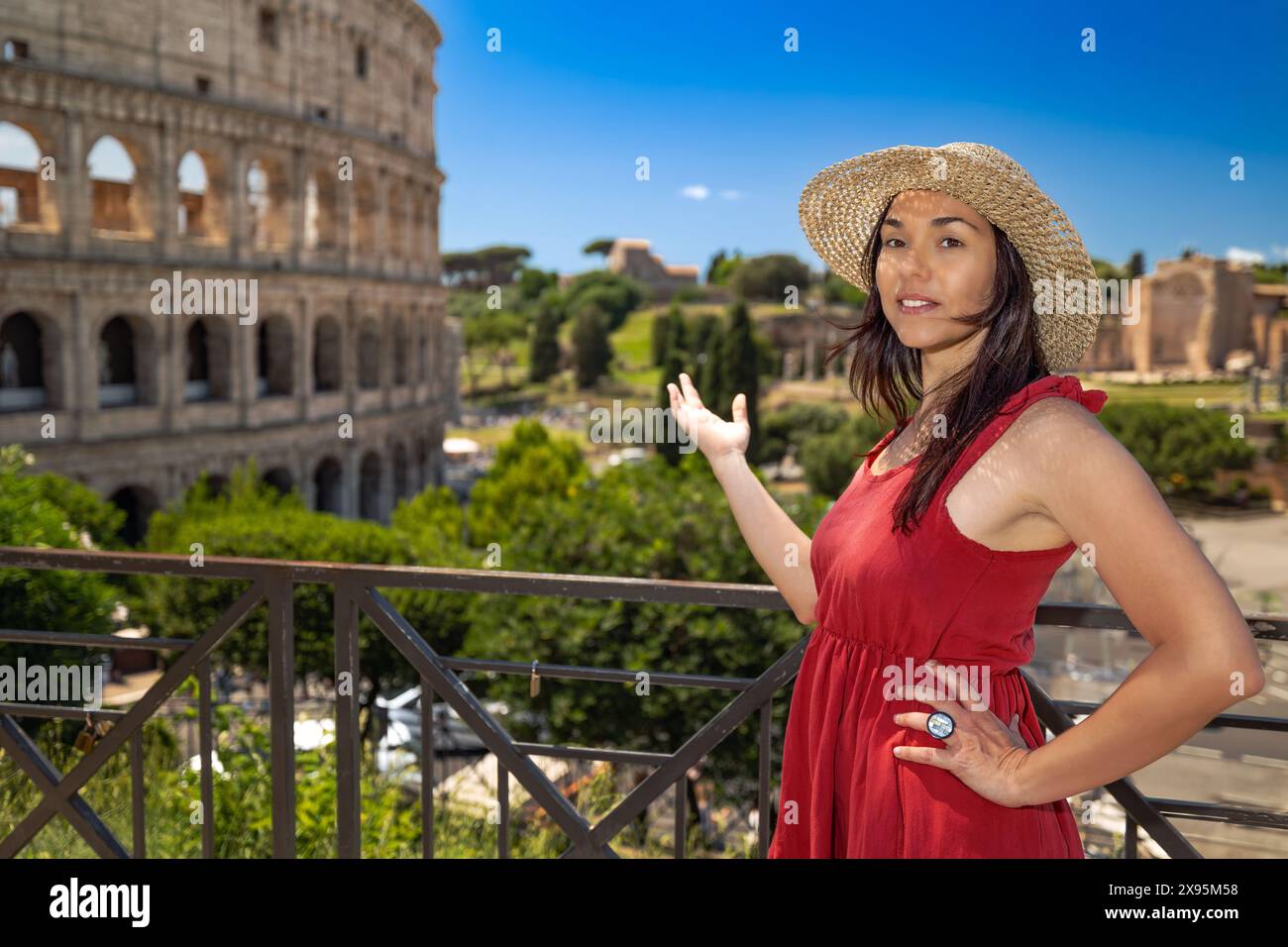 Brunette girl with straw hat admires the majesty of the Colosseum and ...