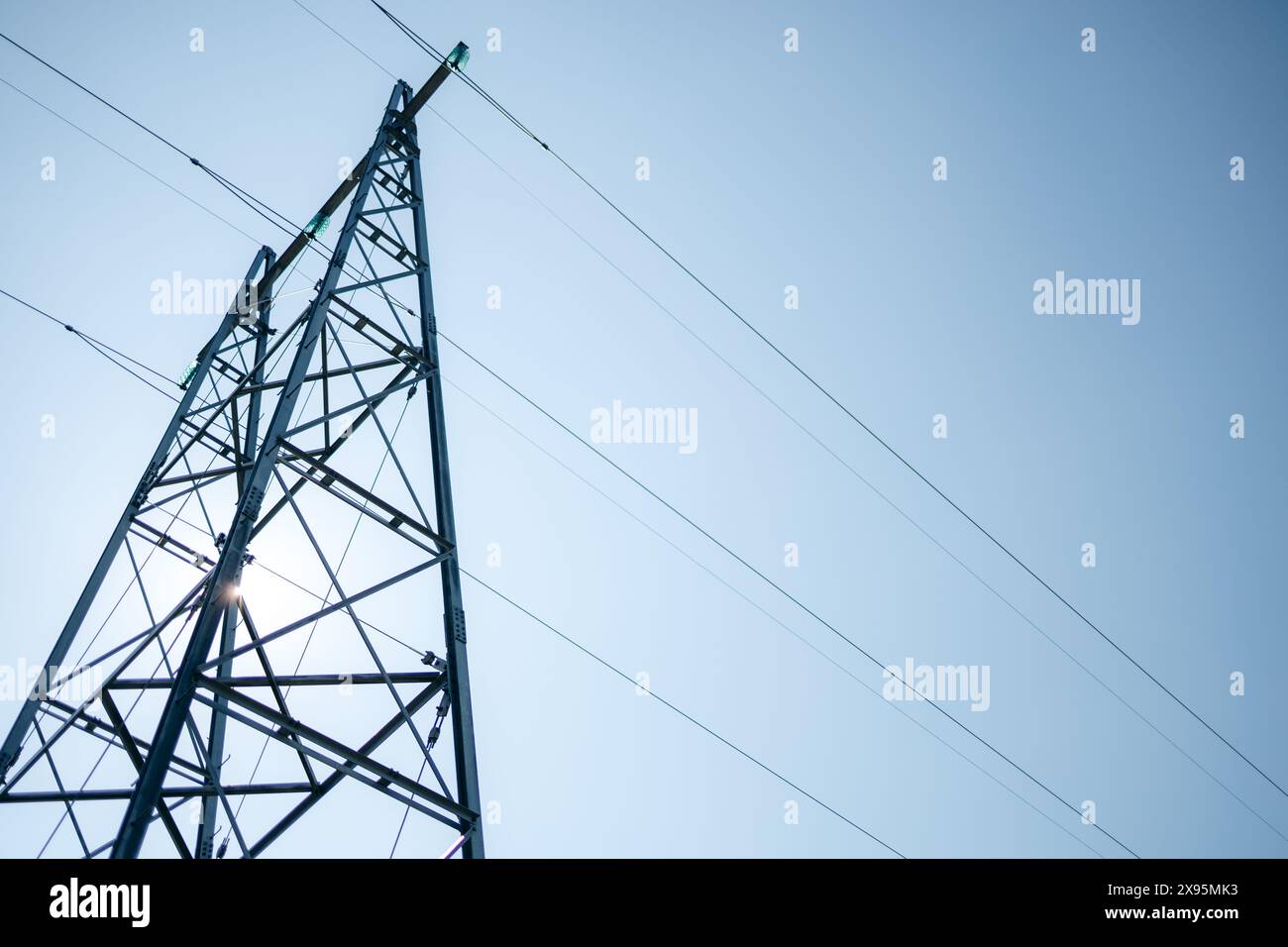 Frogs eye view of an electrical mast and cables, with the sun hidden ...