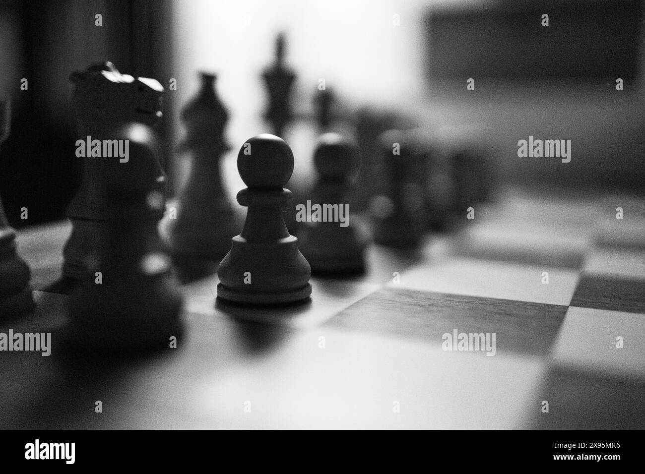Black and white closeup of dimly lit chess pieces, one pawn in focus ...
