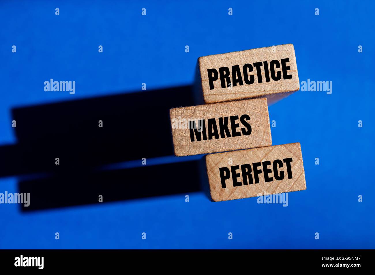 Practice makes perfect words written on wooden blocks with blue ...