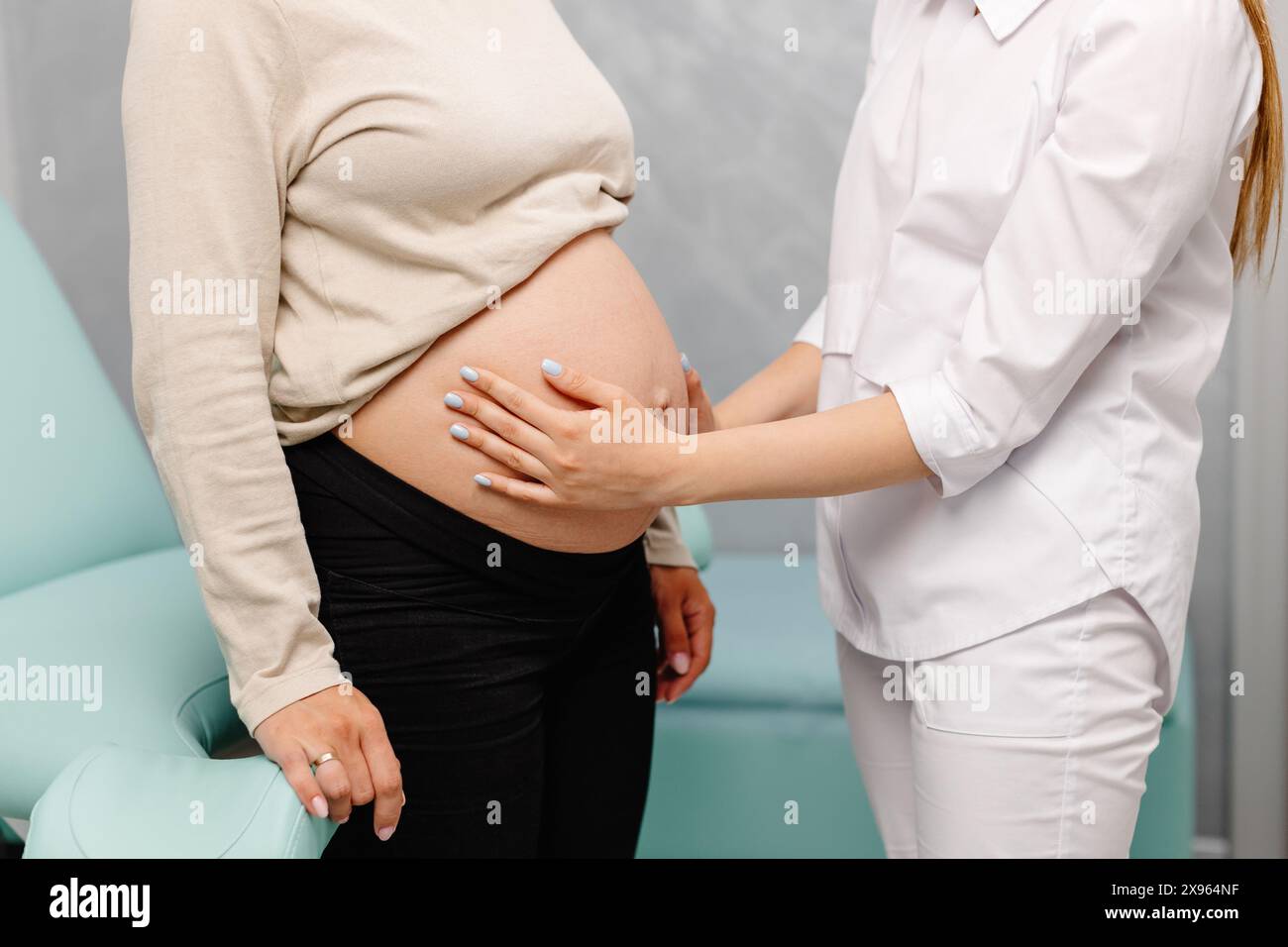 Doctor examining pregnant woman during medical consultation, touching ...