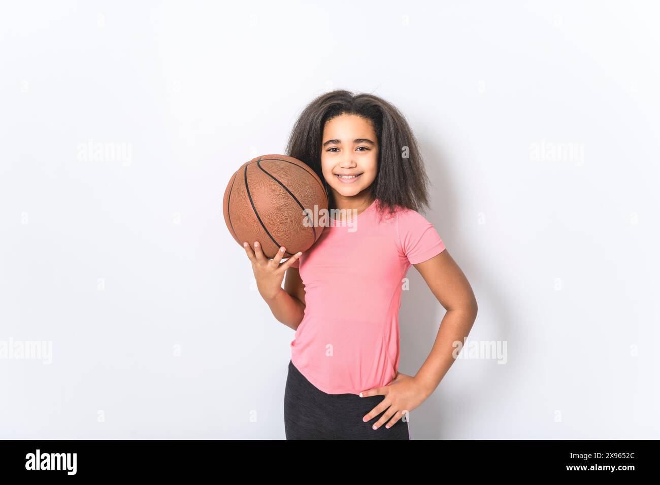 Studio shot of young girl, basketball player over white background ...