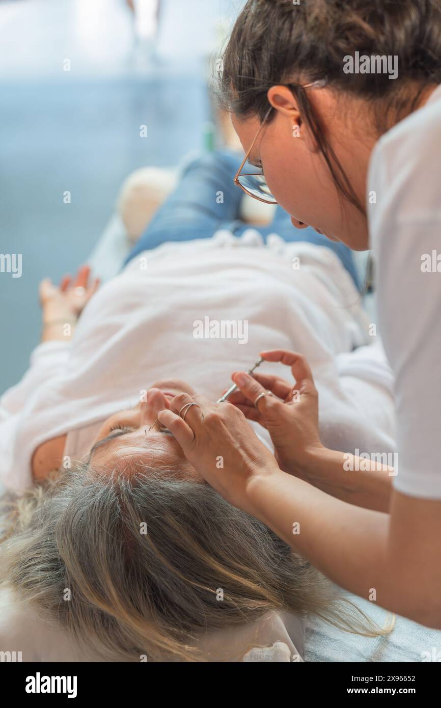 Young girl giving an acupuncture treatment to an elderly lady on the ...