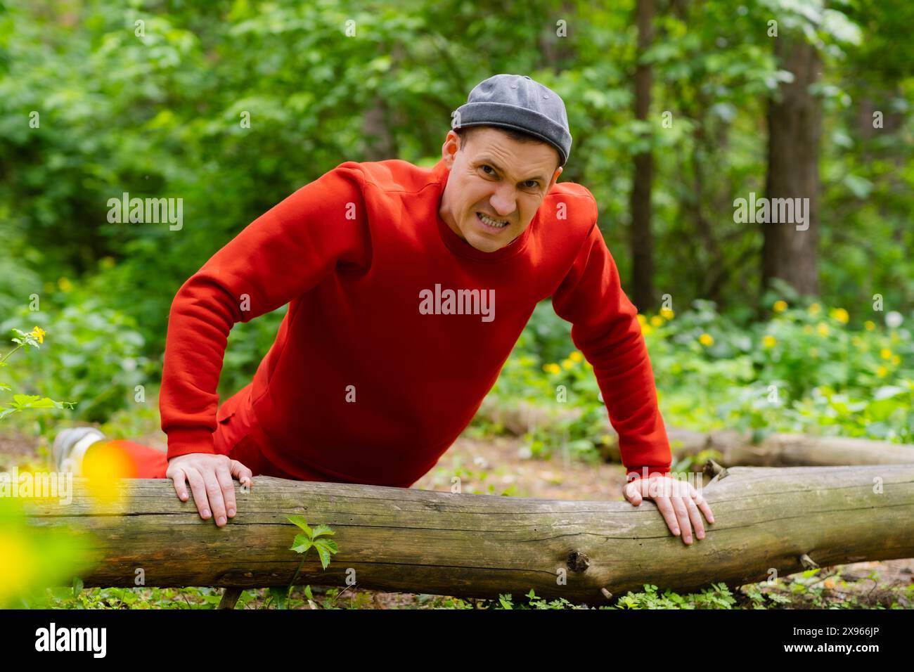 A man performs push-ups using the log as support. The backdrop is a ...