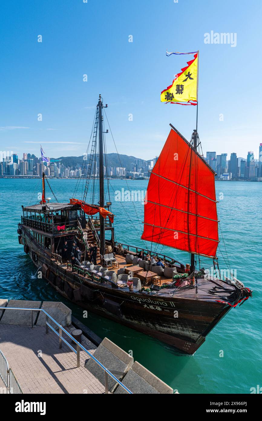 Traditional sailing boat with red sail with high rise buildings in ...