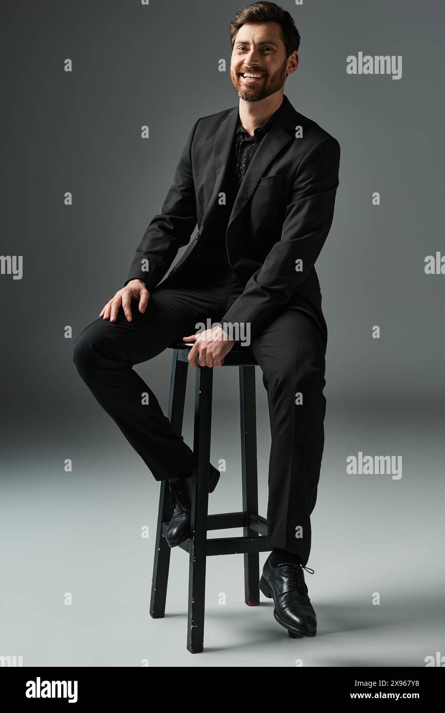 A distinguished man in a suit gracefully sits on a stool Stock Photo ...