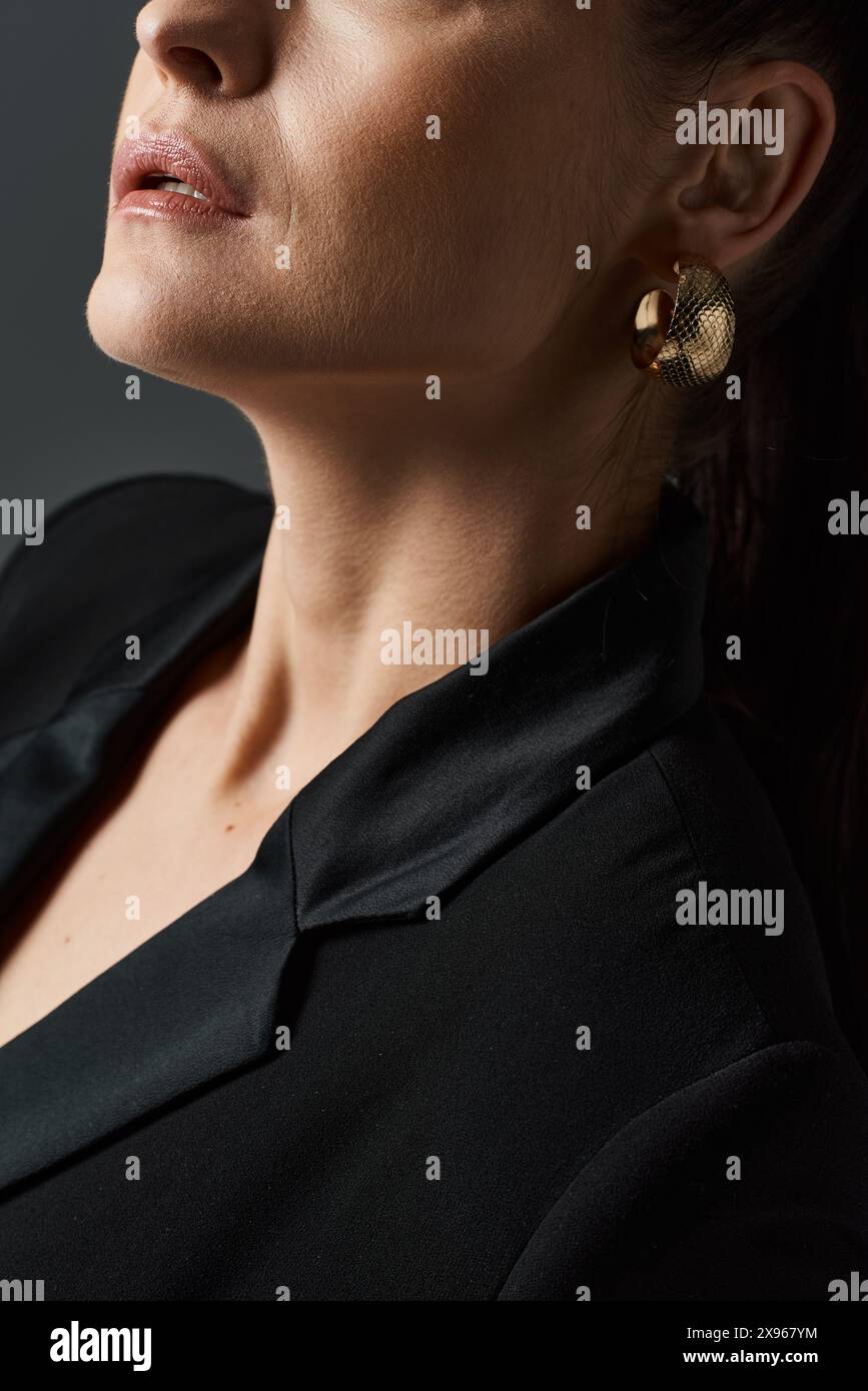 A woman in a black shirt and dazzling gold earrings poses elegantly ...