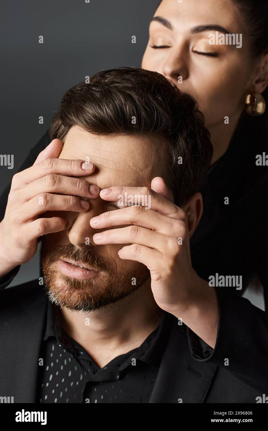 A woman dressed elegantly covers her boyfriend eyes with her hands ...