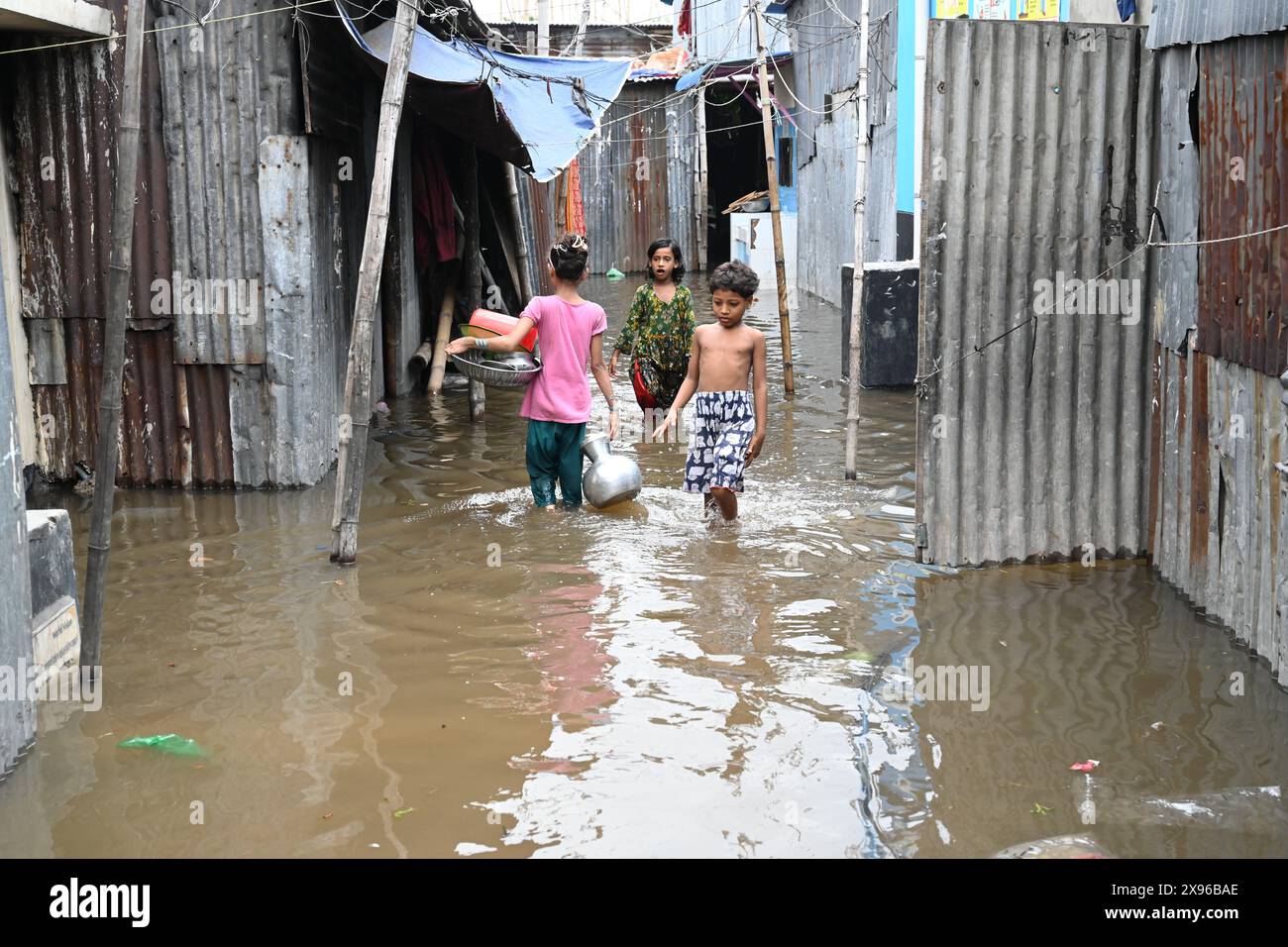Slum children wades through a flooded courtyard following heavy rains ...