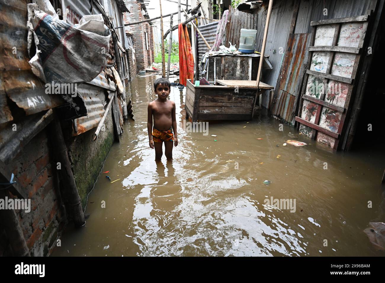 A slum child wades through a flooded courtyard following heavy rains ...