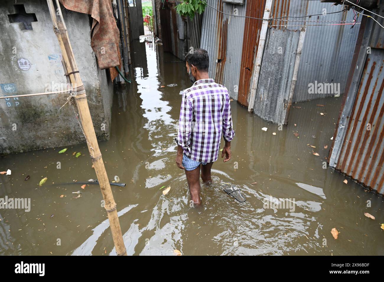 A slum people wades through a flooded courtyard following heavy rains ...