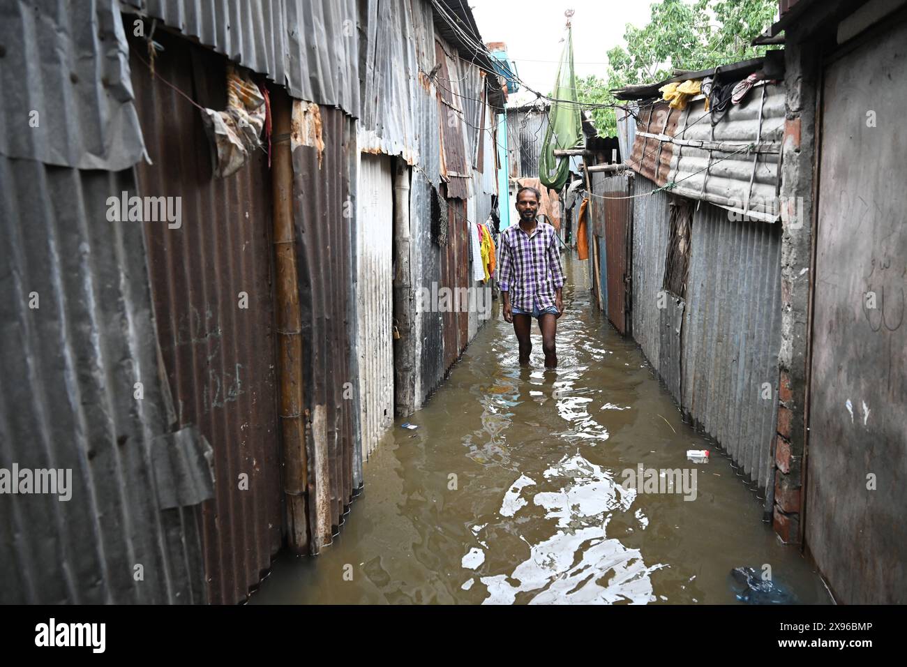 A slum people wades through a flooded courtyard following heavy rains ...