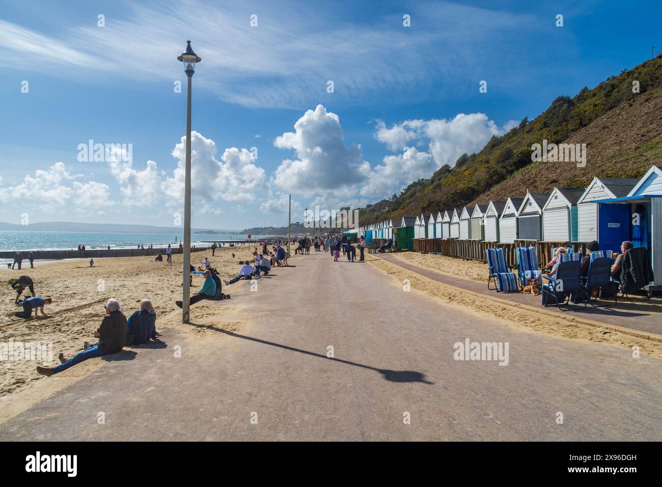 Bournemouth, UK - March 30th 2024: People sitting outside beach huts ...