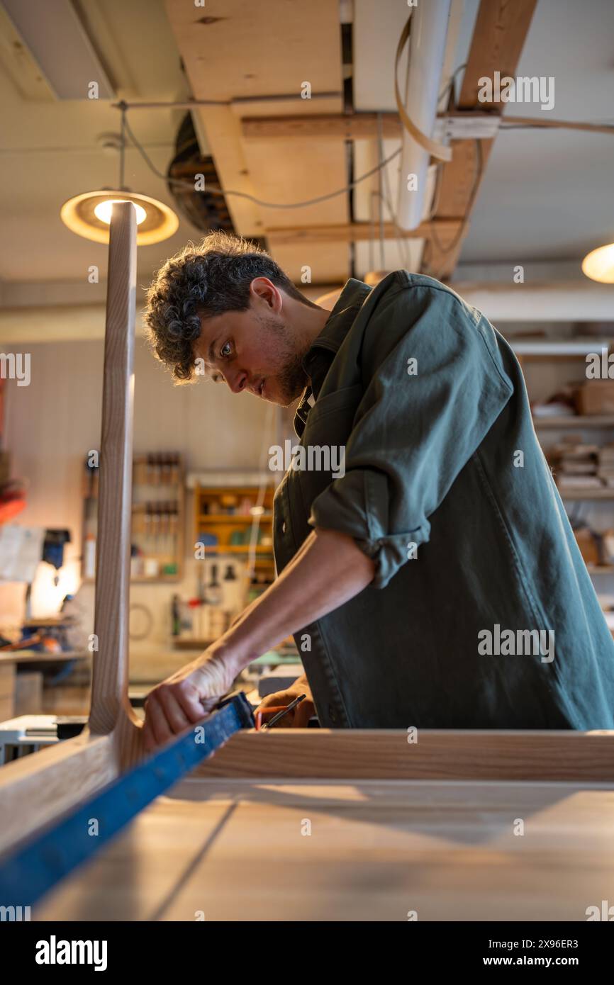 Concentrated carpenter working on making a table, using clamping ...
