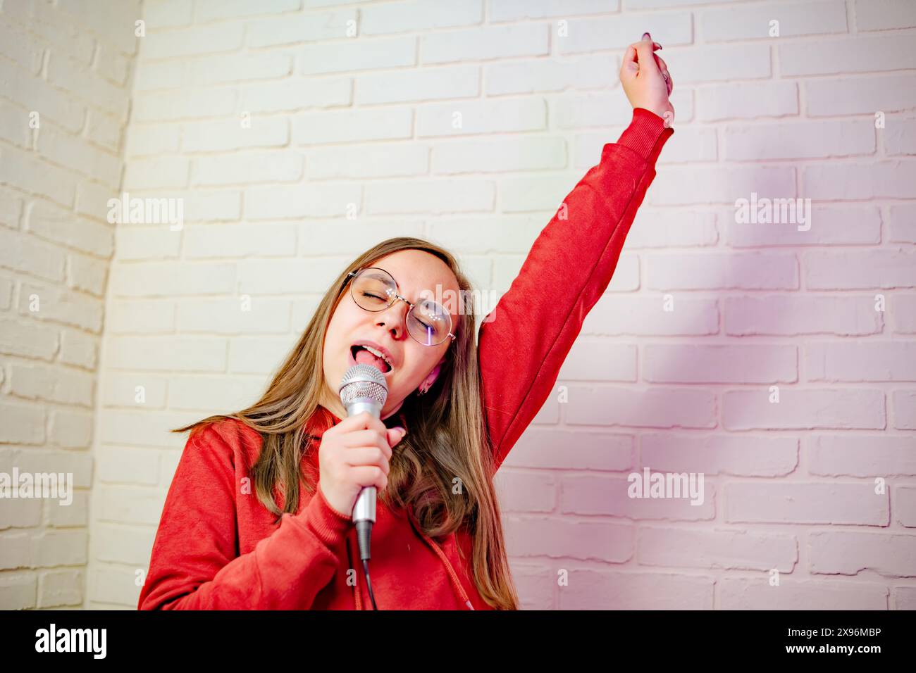 A woman in a red hoodie with a microphone in her hands sings and dances ...