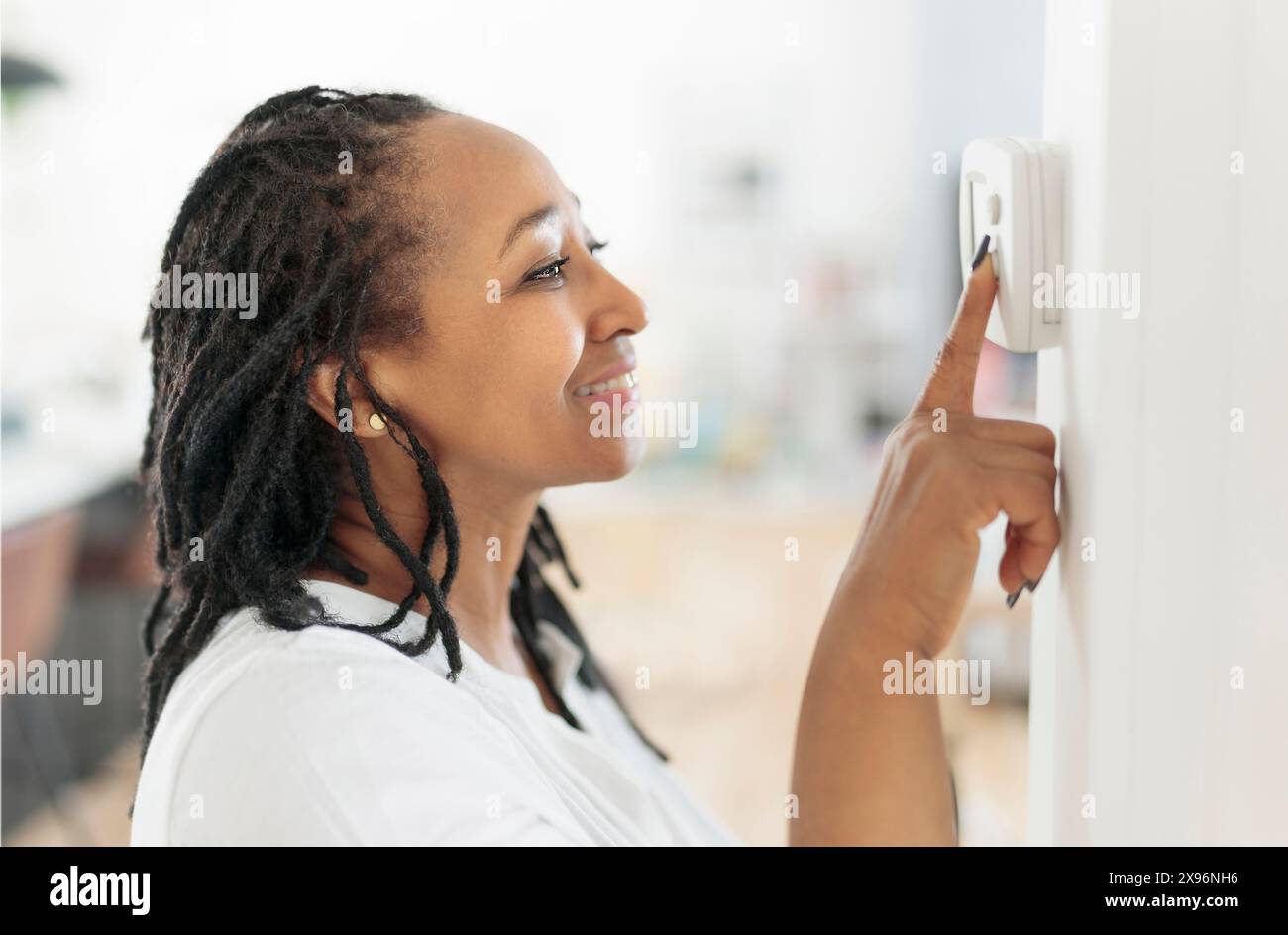 A frican woman lady adjusting the climate control panel on the wall ...