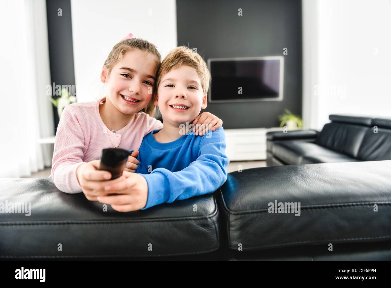 Little brother and sister watching tv on couch Stock Photo - Alamy