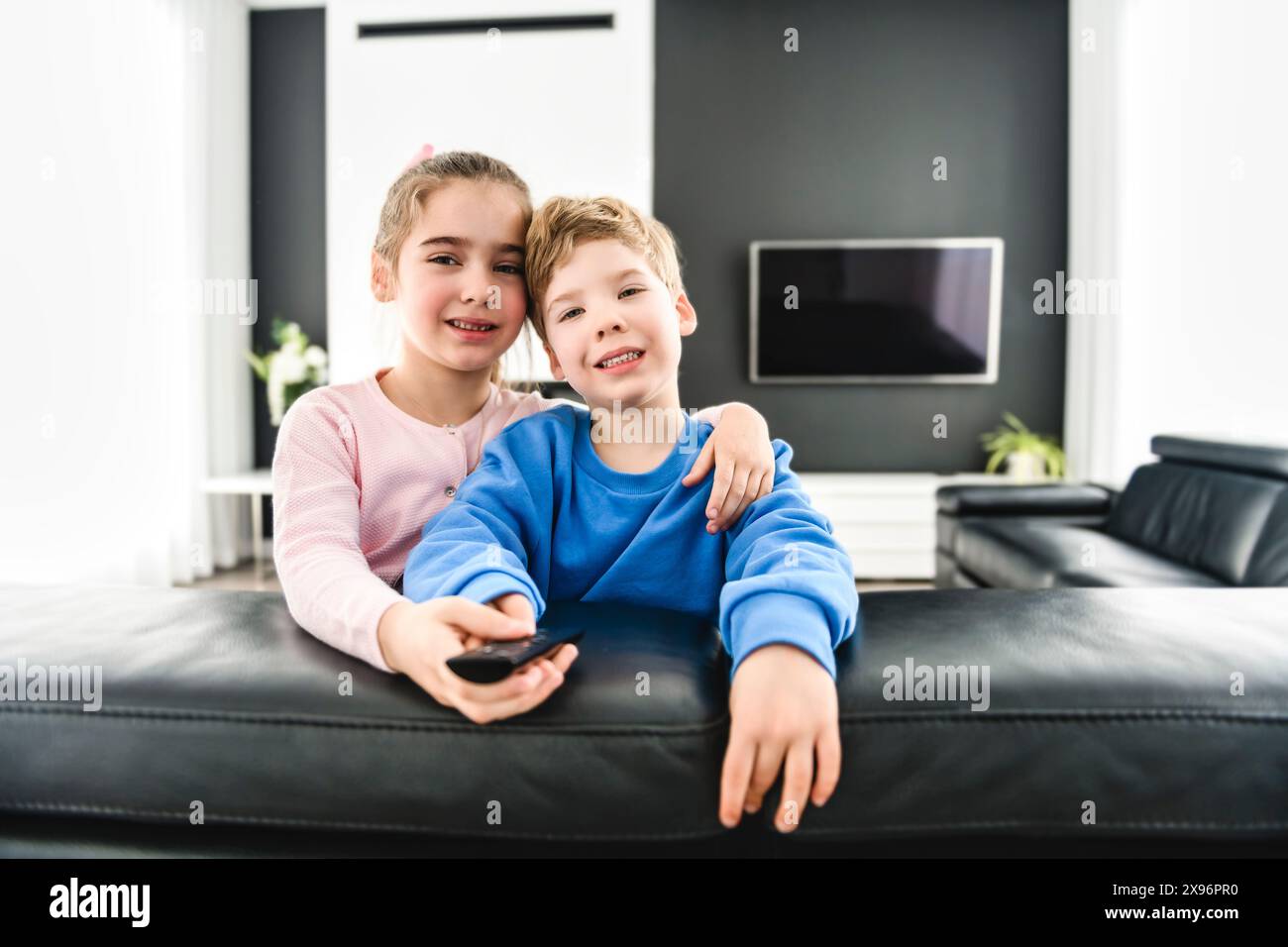 Little brother and sister watching tv on couch Stock Photo - Alamy