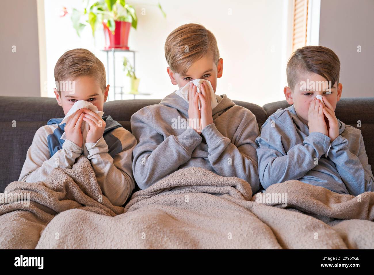 coughing little brothers boys at home having flu on the sofa Stock ...