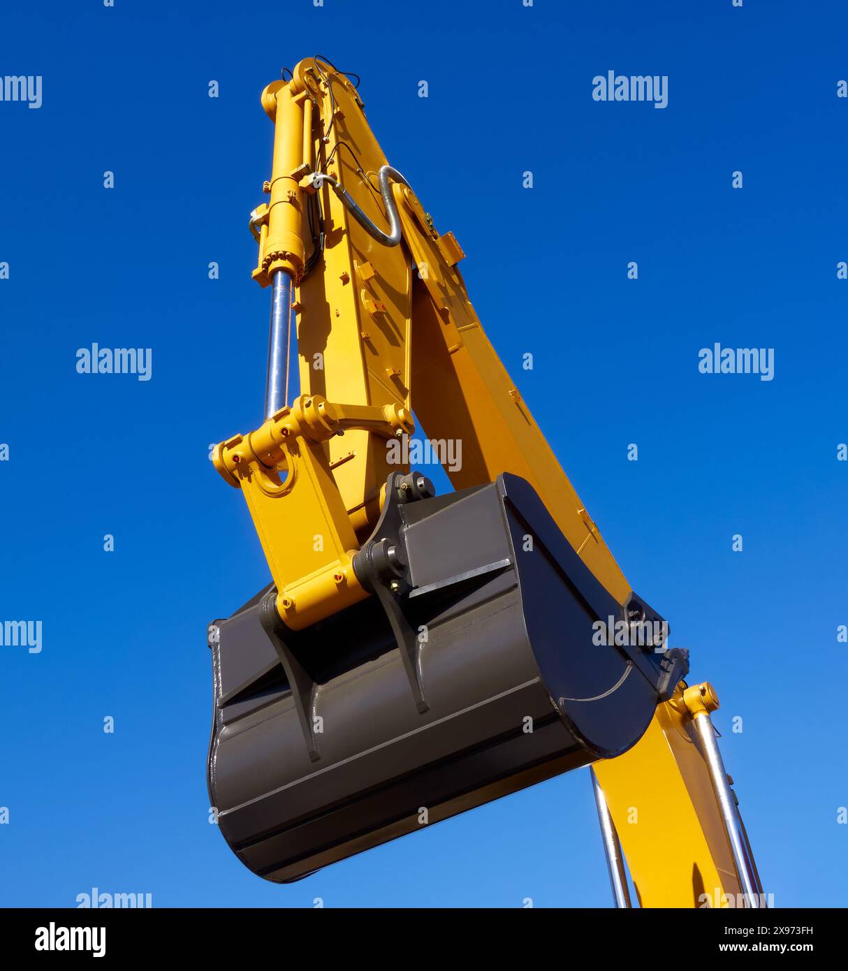 Scoop and hydraulic arm of an excavator, isolated on clear blue sky ...