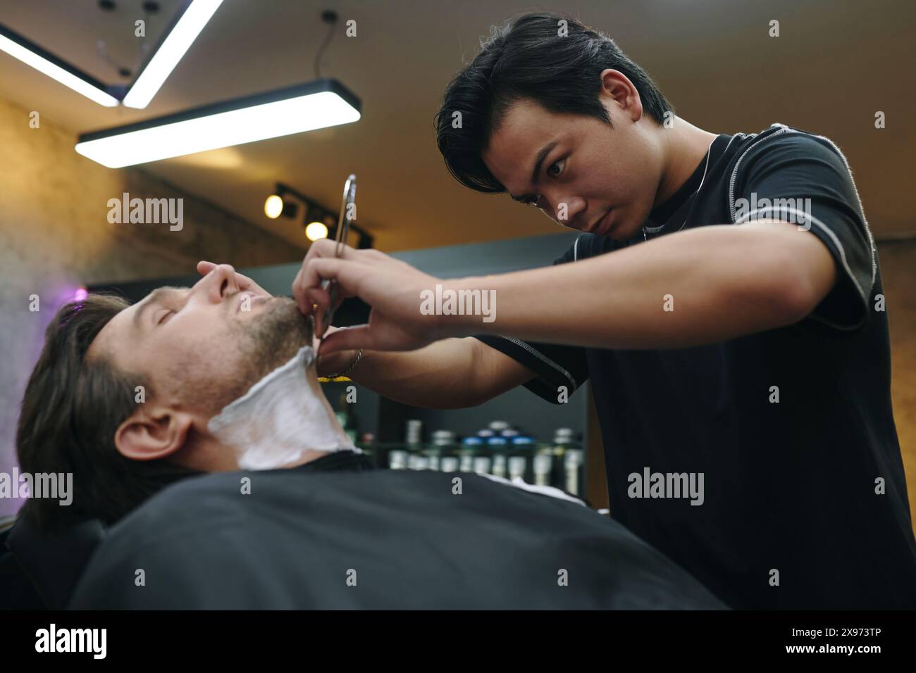 Concentrated barber shaving neck of client with sharp razor Stock Photo ...