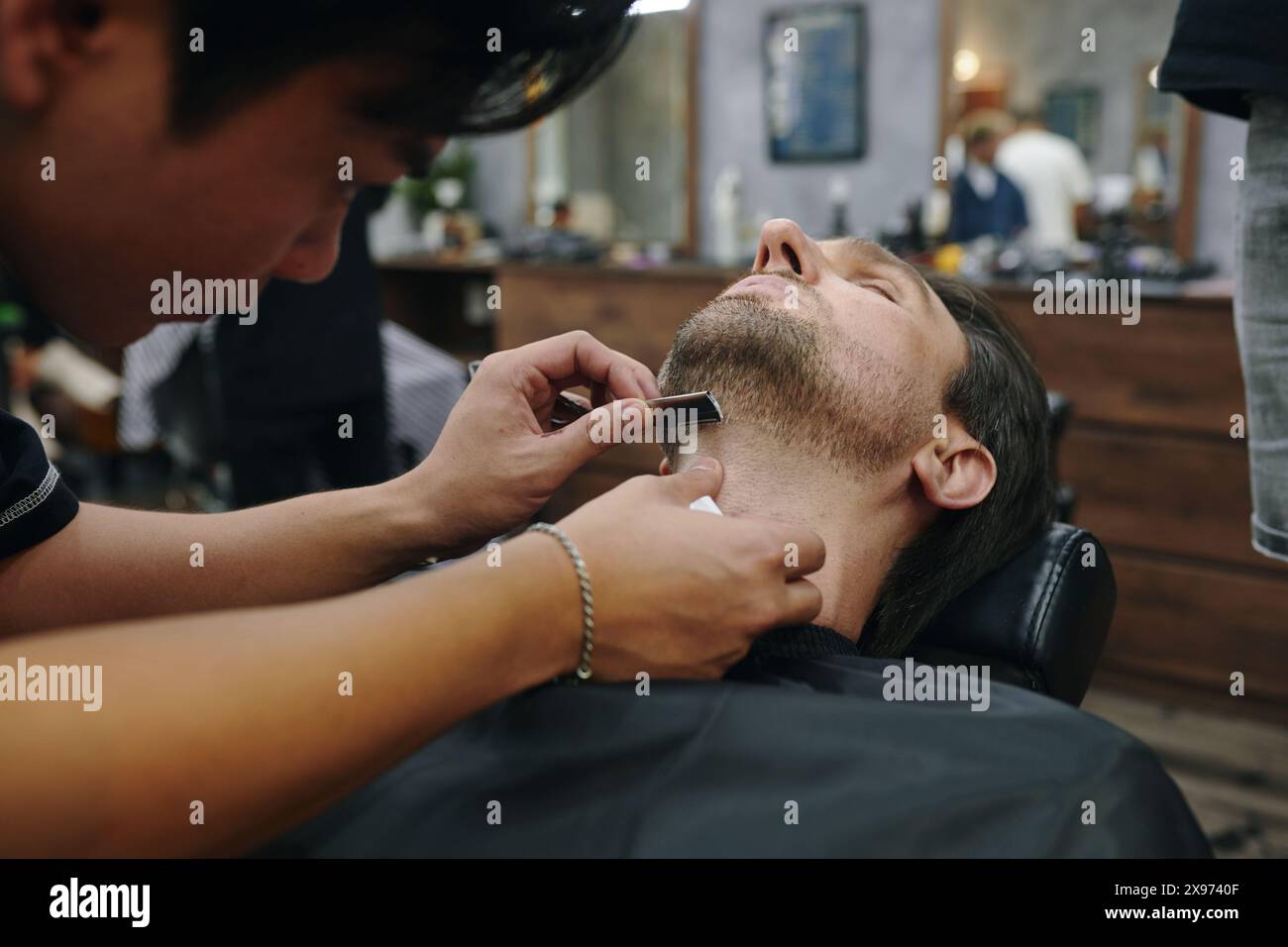 Barber using shavette straight razor when shaving neck of client Stock ...