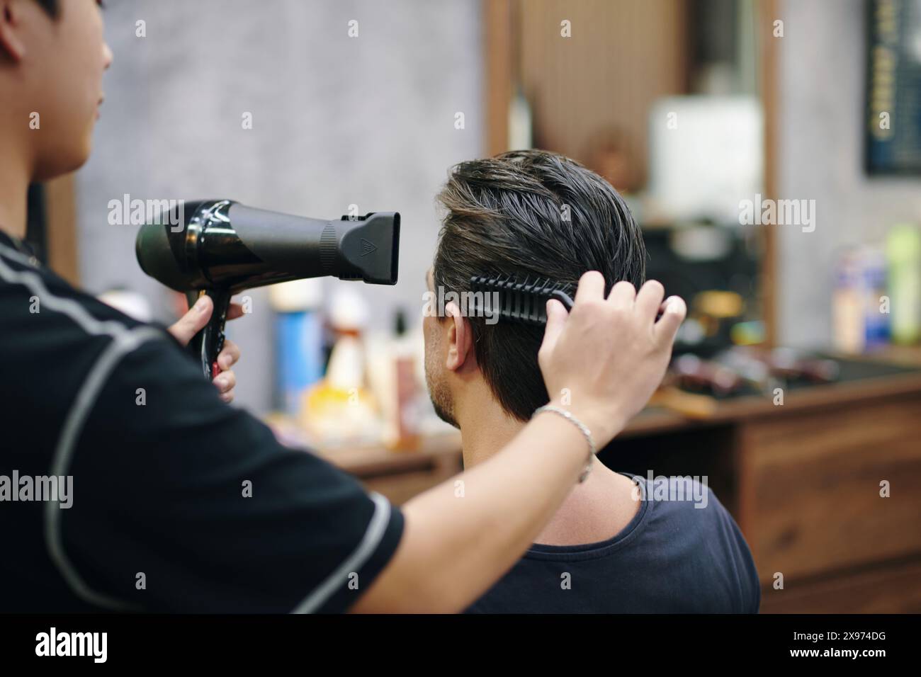 Barber blow drying hair of client after haircut Stock Photo - Alamy