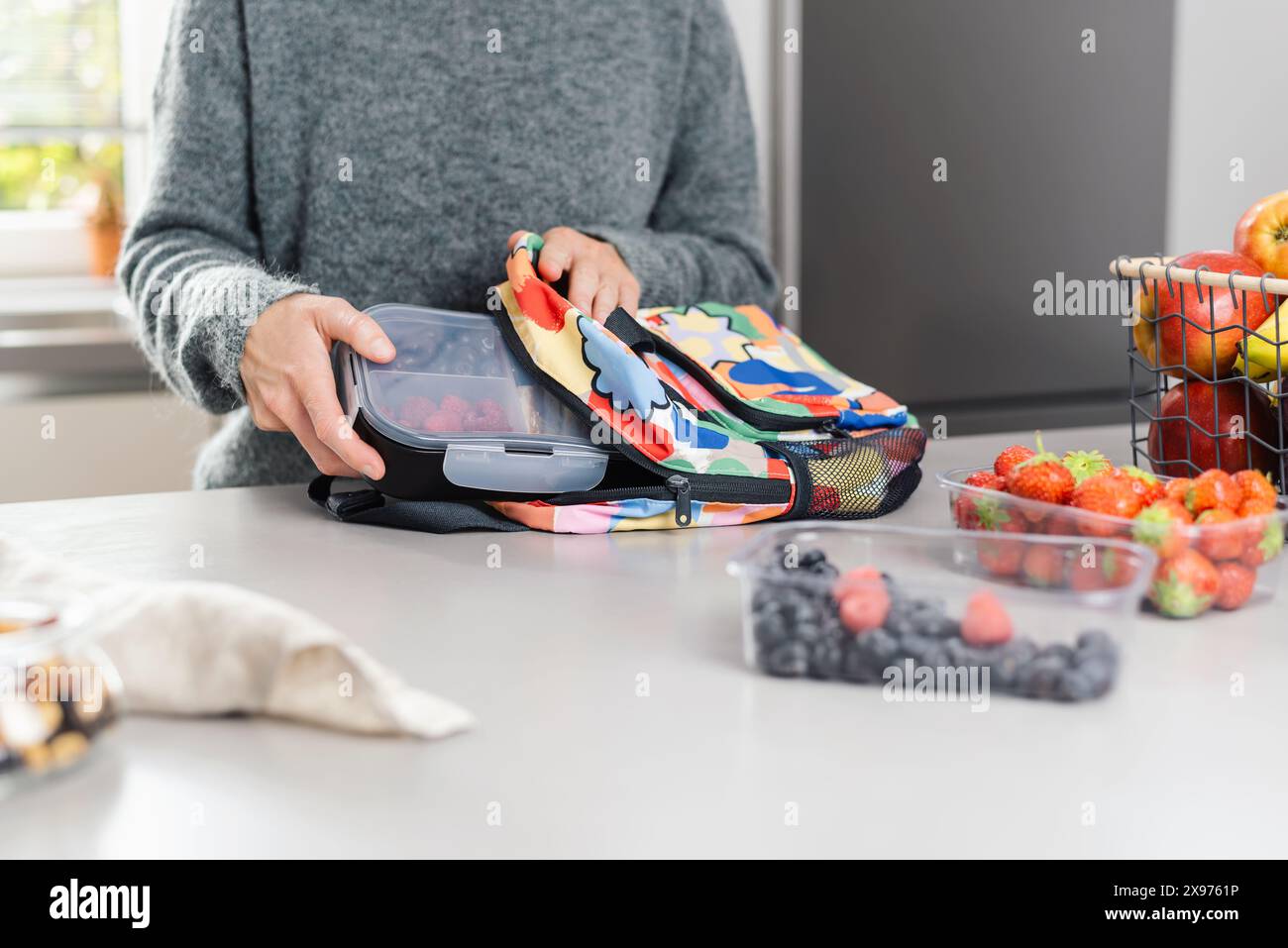 Mom packs a lunch box with snacks lunch in a school backpack in the ...