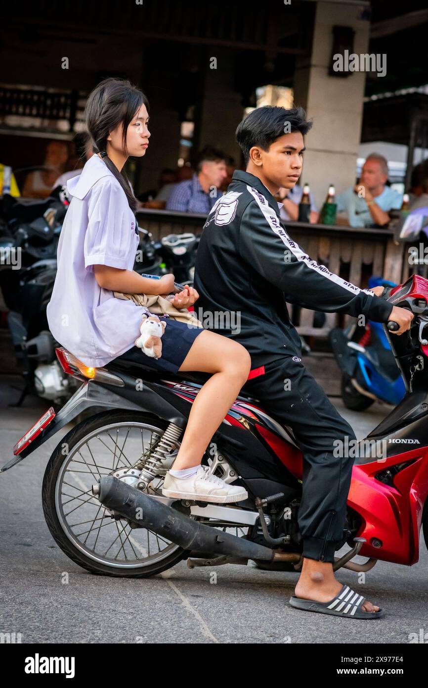 A Thai teenager school girl heads home on the back of a scooter in ...