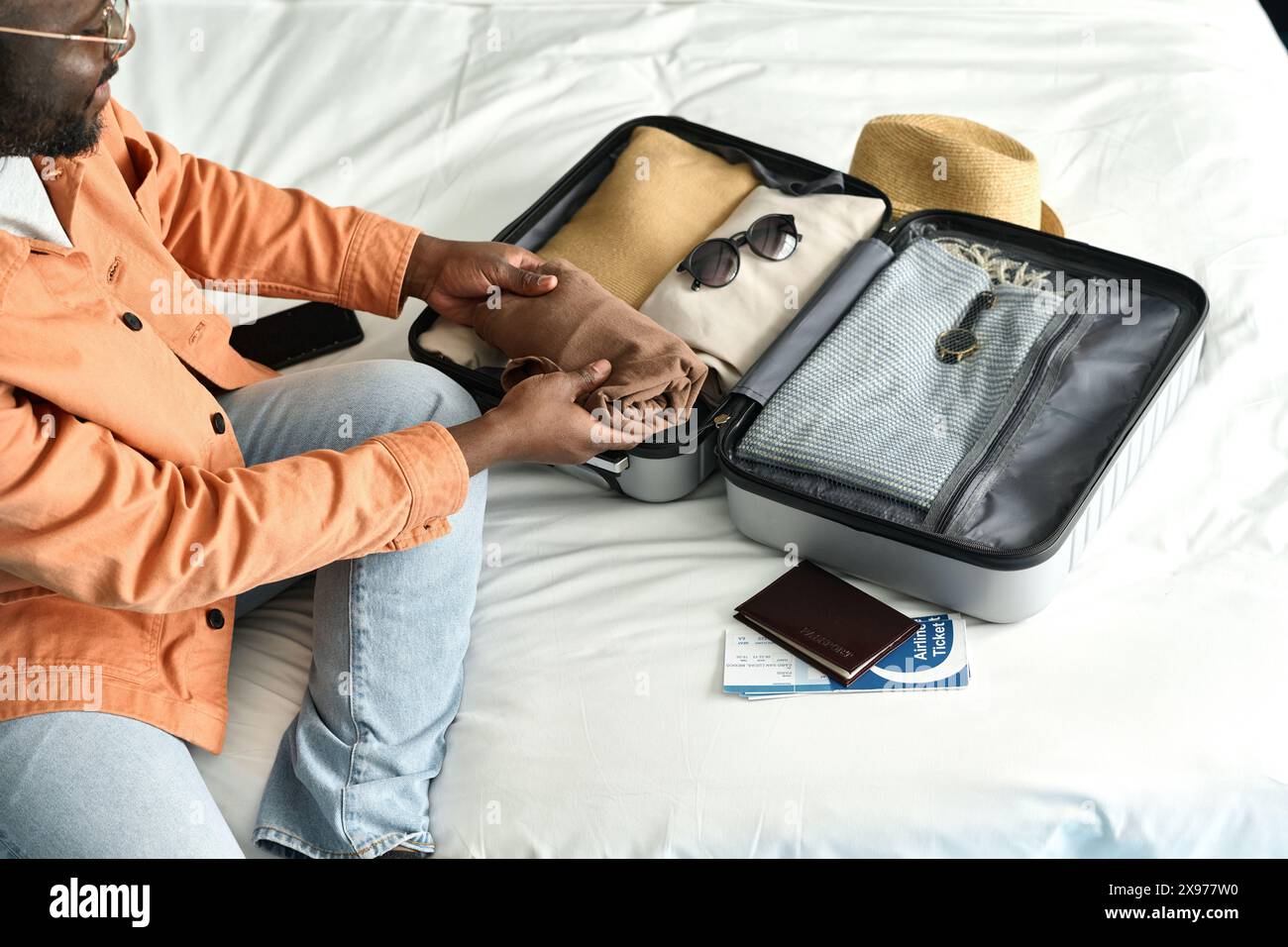 High angle closeup of Black man packing suitcase preparing for travel ...