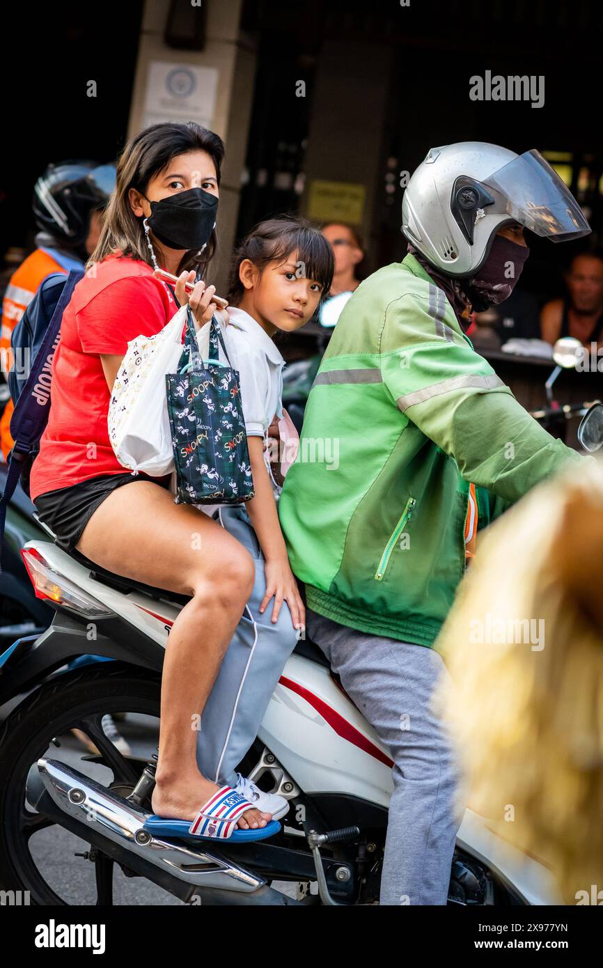 A young Thai school girl and possibly her mother grab a lift on a ...