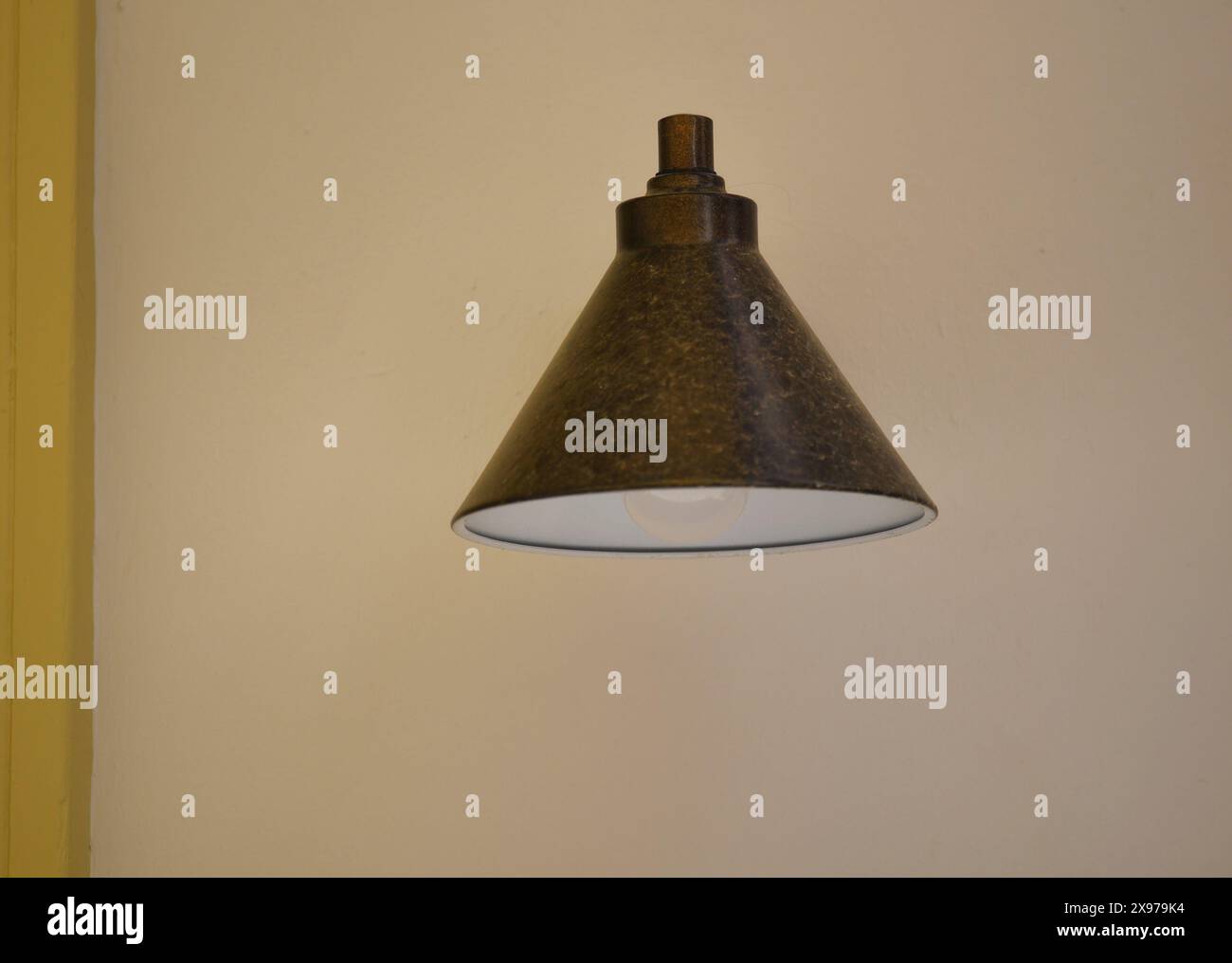 Cone shaped wall mounted metal light fixture on a stucco wall in ...