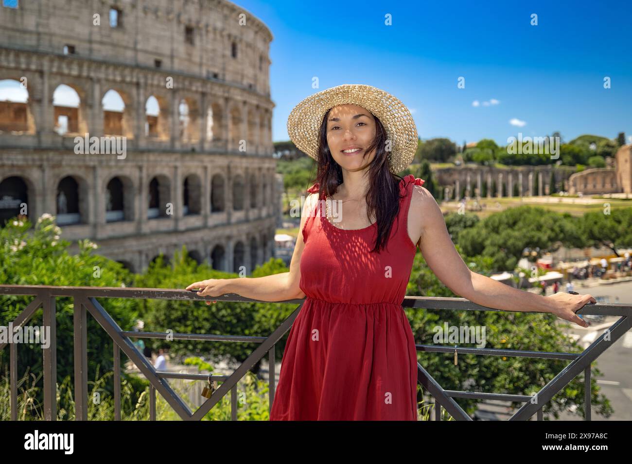 Brunette girl with straw hat admires the majesty of the Colosseum and ...